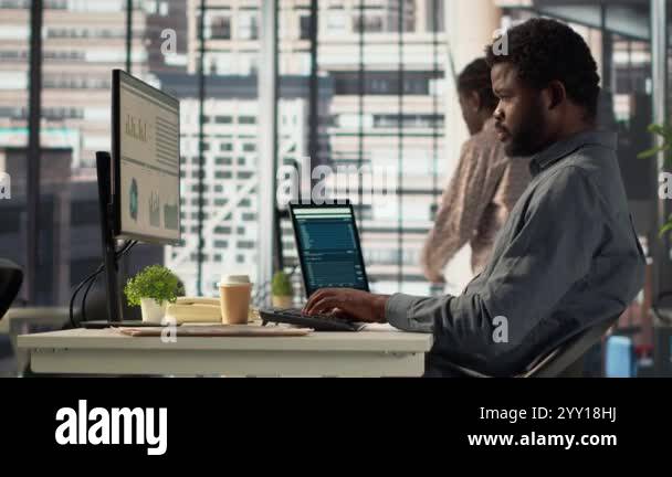 African american company worker taking a break to stretch his back in the office, trying to ...