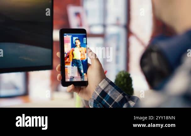 Man in workspace watching videos on social media on smartphone. Person ...