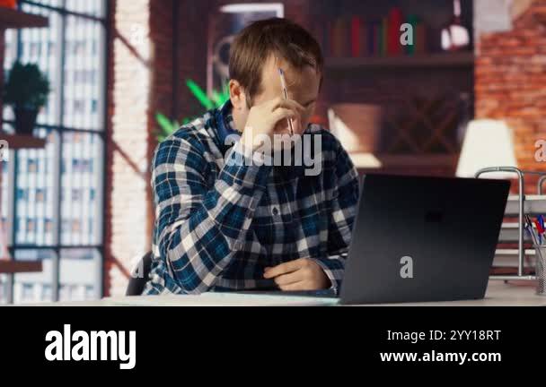 Stressed man in home office scratching head with pen, upset after ...