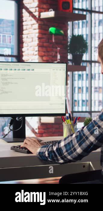 Man In Home Office Looks At Green Screen Tablet And Computer Typing And Executing Programming