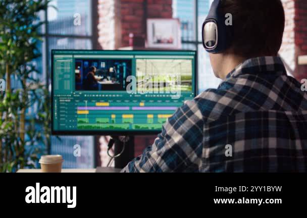 Video editor wearing headphones doing video montage, using specialized ...