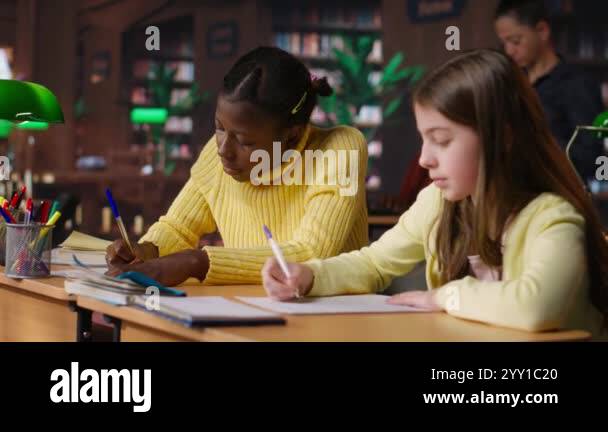 Diverse scholars helping each other finish the homework at the library ...