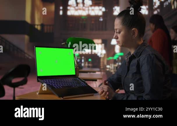 Professional librarian working on her laptop next to mockup screen in a ...