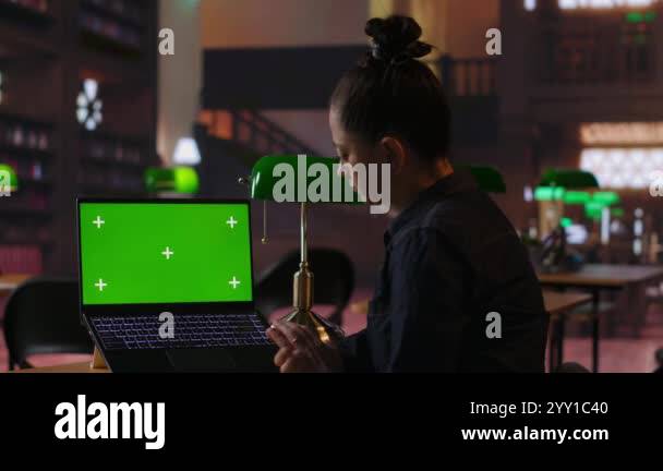 Professional librarian working on her laptop next to mockup screen in a ...