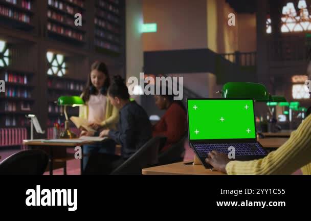 Black scholar reading information via internet next to chroma key in a library, focusing on ...