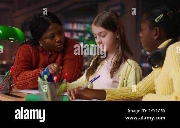 Female teacher assisting pupils with class homework and mentoring ...
