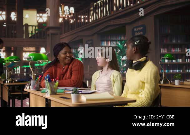 Diverse teen girls working with a tutor to complete class notes in a ...