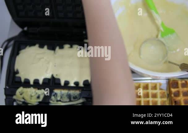 Cook pouring waffle batter into a hot waffle iron creates golden ...