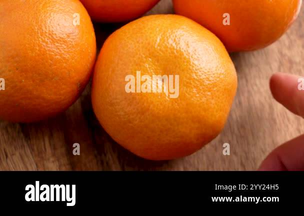 Hand reaching for a ripe tangerine. Bright orange peel of Spanish fruit ...