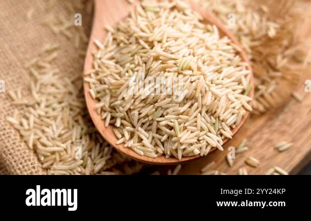 Organic unprocessed basmati rice placed in a wooden spoon on burlap ...