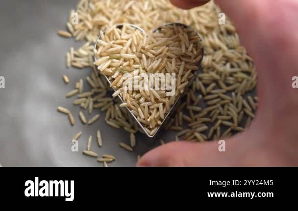 Hand carefully removes a heart-shaped metal mold from pile of raw ...