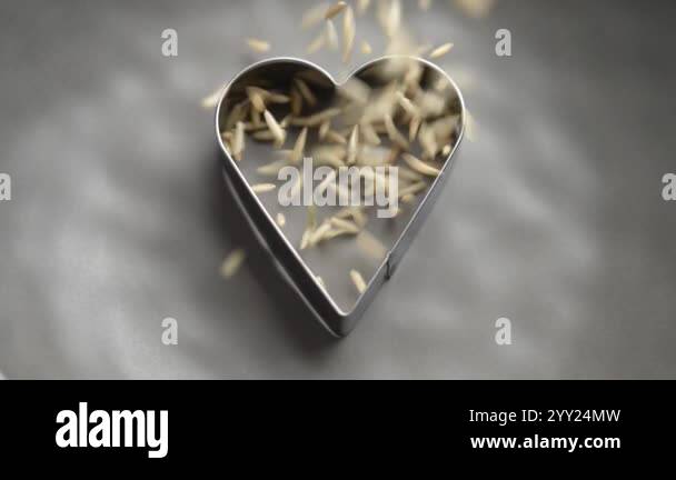 Close up of unprocessed basmati rice falling into a metallic heart ...