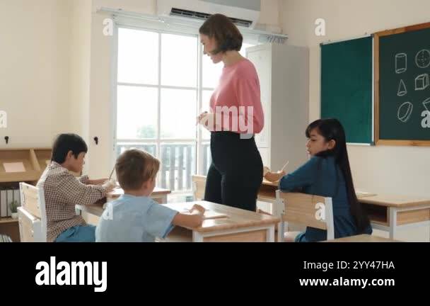 Caucasian teacher walking and check student homework at classroom while ...