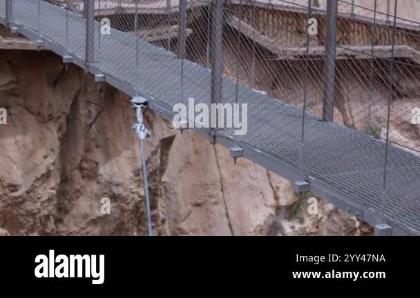 A suspension bridge stretches across a deep canyon, constructed from ...