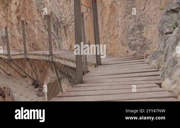 A wooden walkway stretches along a rocky cliff, providing an ...