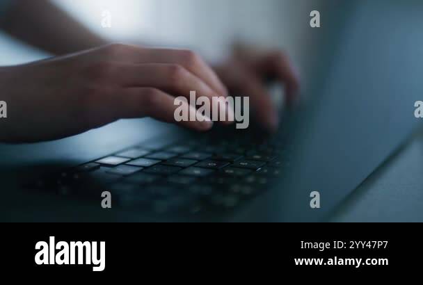 A close-up of hands typing on a laptop keyboard while writing an email ...