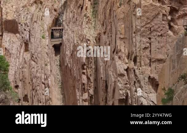 A narrow canyon reveals towering rocky cliffs under a clear sky ...