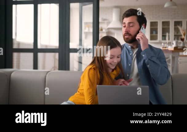 Mischievous Caucasian little girl daughter kid interfering dad from remote freelance job angry ...