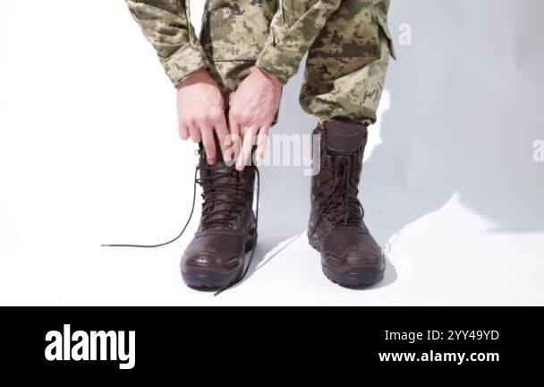 A cropped view of a young man wearing military uniform is putting on ...