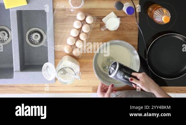 Woman mixing pancake batter with mixer in kitchen top view. Chef ...