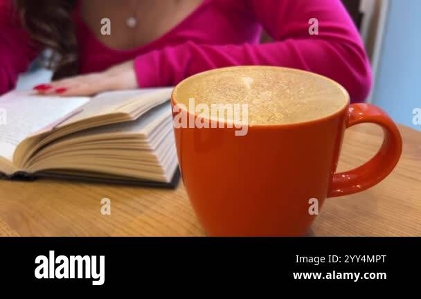 Young asian female relaxing in modern cafe reading book and drinking ...