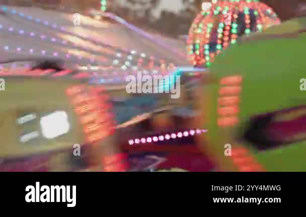 A dizzying, fast carousel ride at a funfair at night with flashing ...