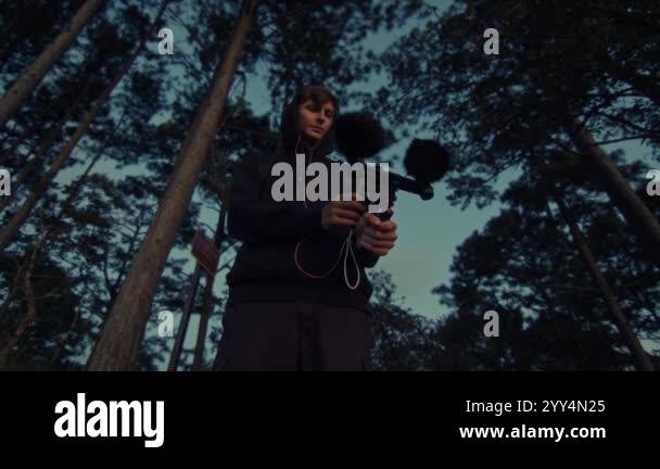 A young man enthusiastically captures various natural sounds outdoors ...