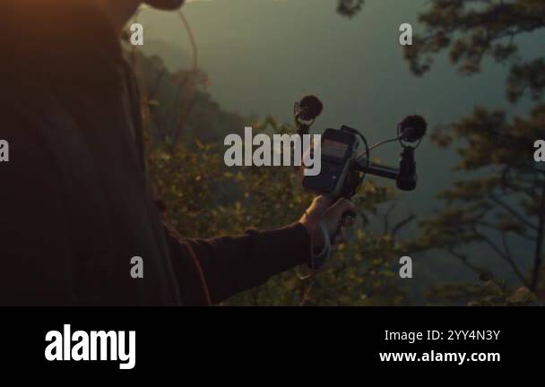 A young man enthusiastically captures various natural sounds outdoors ...
