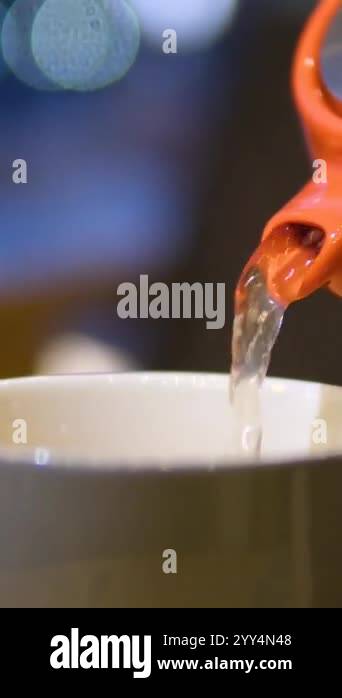 Making hot tea on the kitchen table. Boiling water is poured from the ...