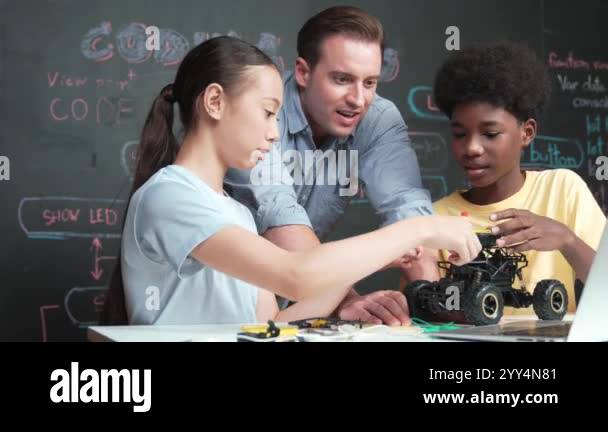 Caucasian teacher pointing at laptop screen while explain car model system at blackboard with ...