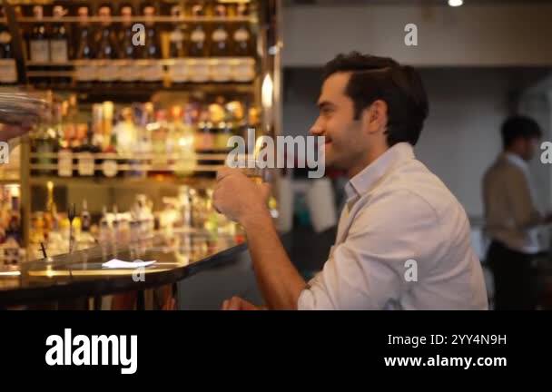 Smiling smart man drinking cocktail in Old fashioned while bartender ...