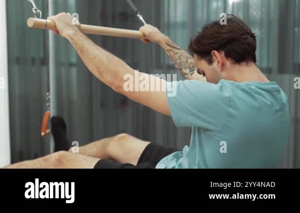 Man performing seated core exercise on pilates trapeze holding bar to ...