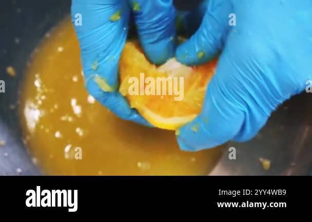 Chef squeeze orange juice close up. The woman hands in blue gloves ...