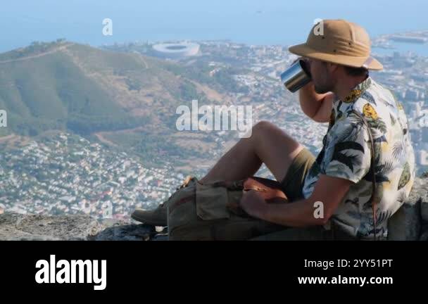 man hiker in boots drinking a hot drink from a mug sitting on a ...