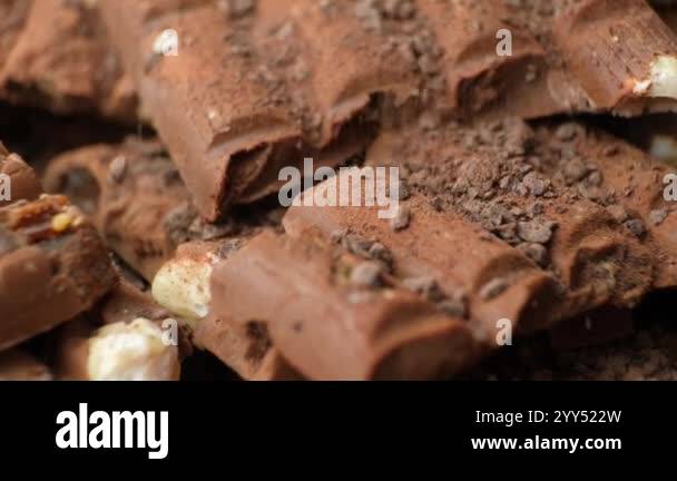 Grated chocolate chips pouring on rotating nut chocolate bars, slow ...