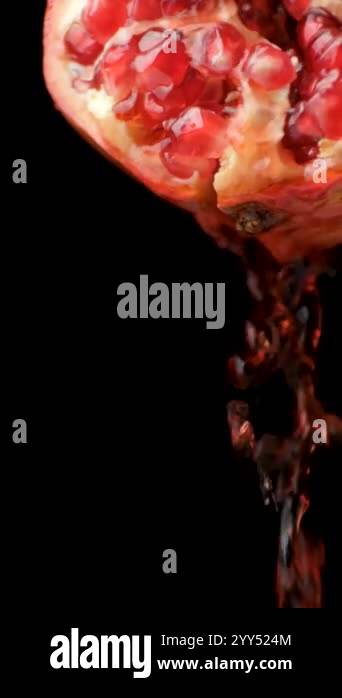 Pomegranate juice dripping from half pomegranate, vertical slow motion ...