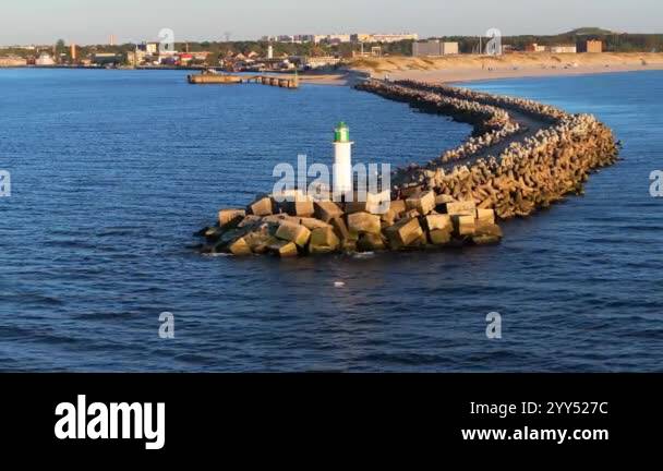 A breakwater of concrete blocks and tetrapods leads to a green topped ...