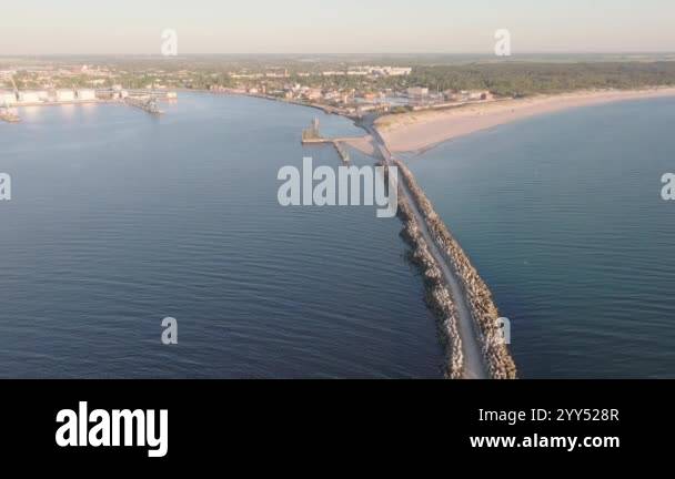 A long breakwater lined with rocks extends into the water, with a sandy ...