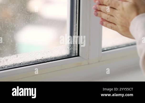 Womans hand checking cold draft from the glasses of window ...