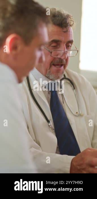 Vertical Screen: Senior doctor and a male patient reviewing medical ...