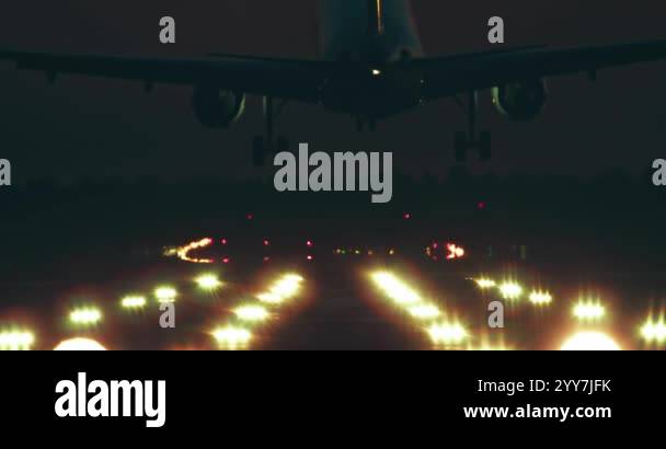 Slow motion video of a plane landing on an airport runway at night ...