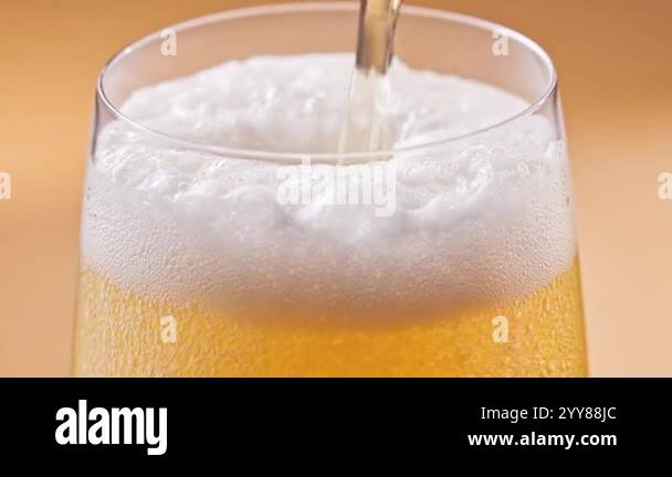 Cold craft light beer pouring to full glass, slow motion close up ...