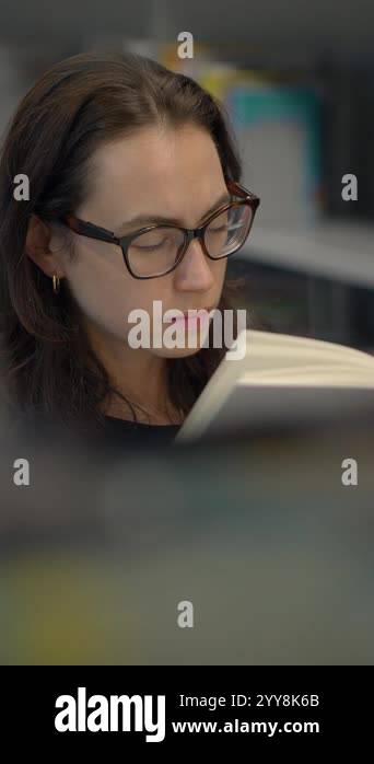 A woman is intensely focused on reading a book within a contemporary ...