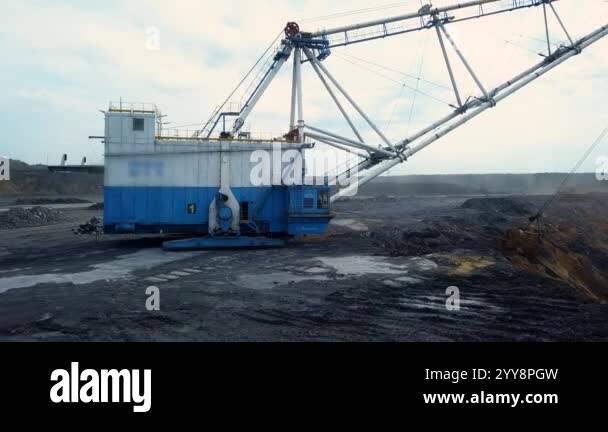 A large blue excavator is actively working on a mining site beneath an ...