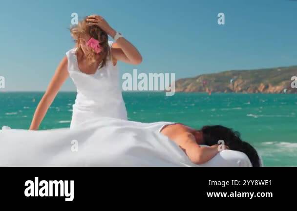 Professional masseuse arranging white cloth on female client, blown by ...