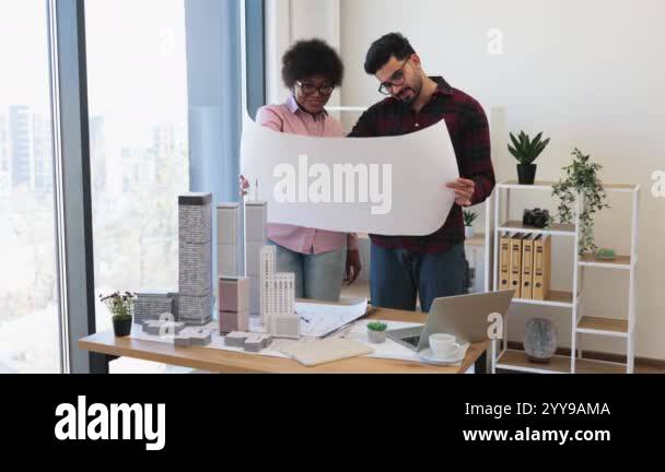 Indian man and African woman architects analyzing blueprints for city ...
