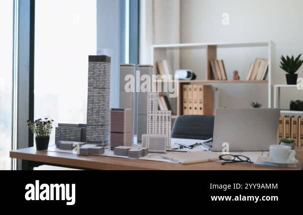 Modern office desk features architectural model and laptop setup ...