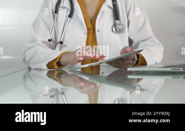 Female doctor, wearing yellow blouse under a medical coat, is using ...