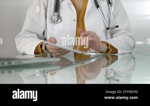 Female doctor, wearing yellow blouse under a medical coat, is using ...