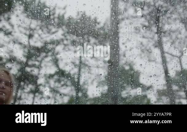 Close-up of a hand drawing mountain shapes on a car window covered with ...